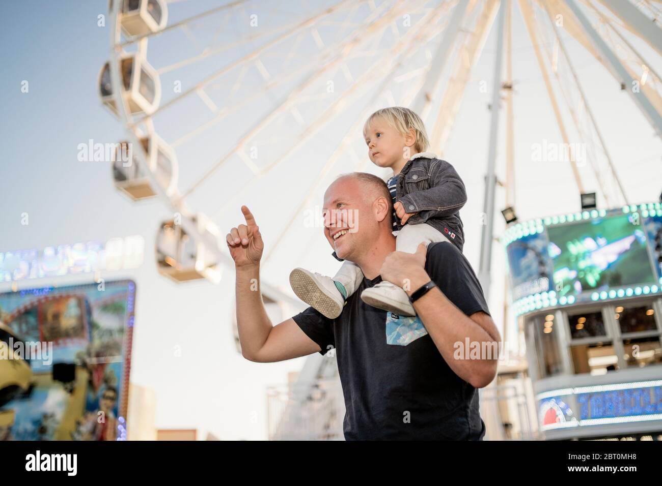 Happy father with his little piggybacked son in an amusement park Stock ...