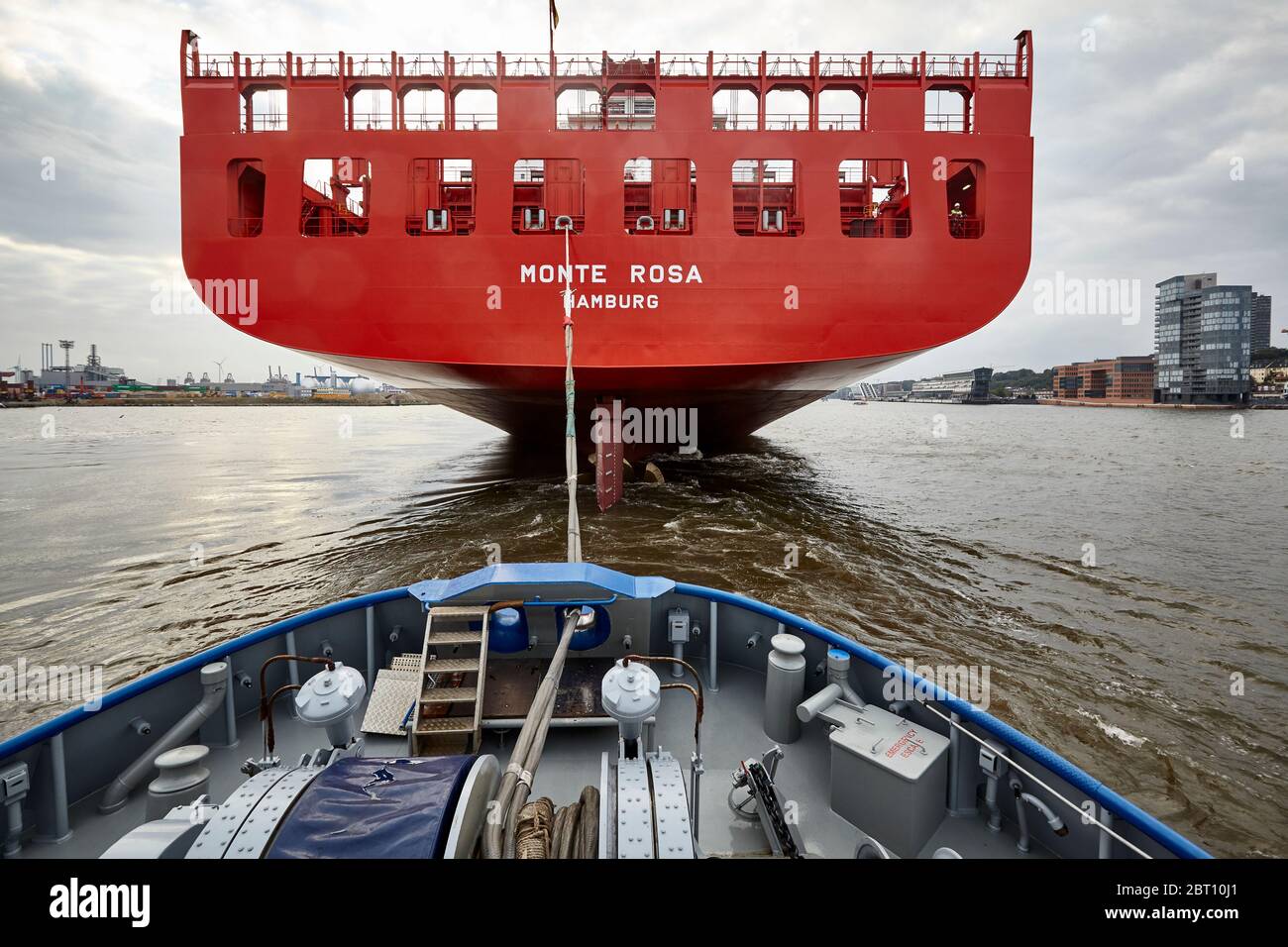 A tugboat steers the container vessel Monte Rosa at it's stern just ...