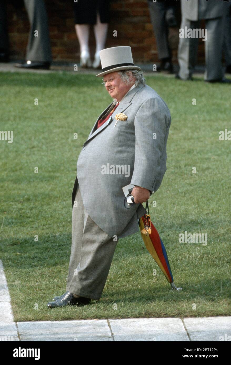 A smartly dressed large man sits on his umbrella seat at the Royal ...