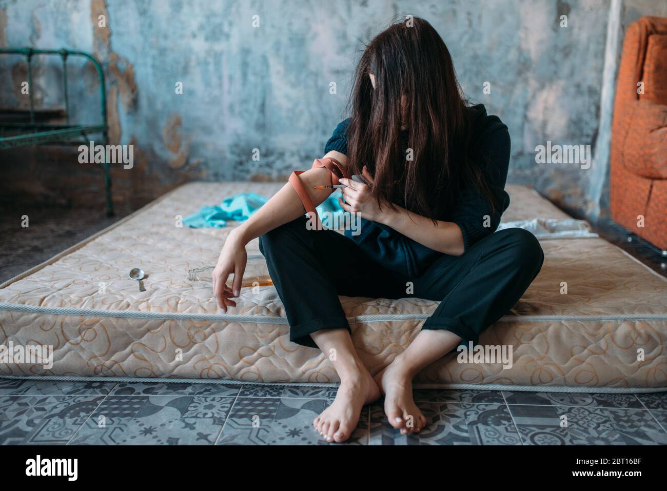 Woman drug addict with a syringe doing an injection dose in the arm ...