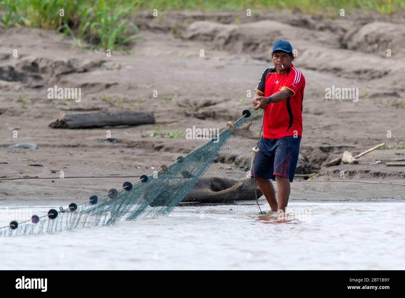 Fisherman with cigarette in mouth pulls in net fishing on the Amazon ...
