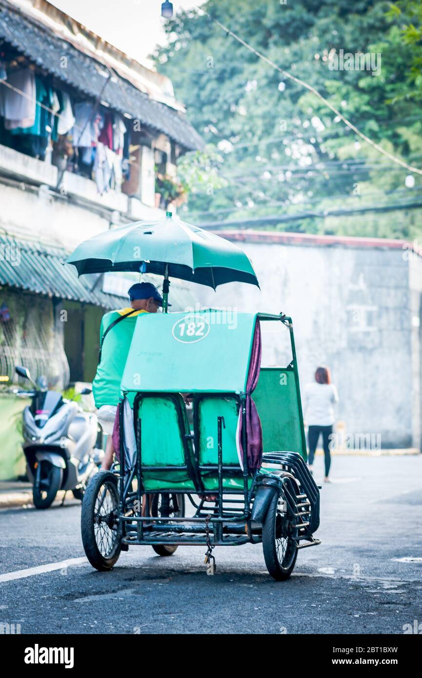A traditional pedicab or rickshaw makes it way through the streets of ...