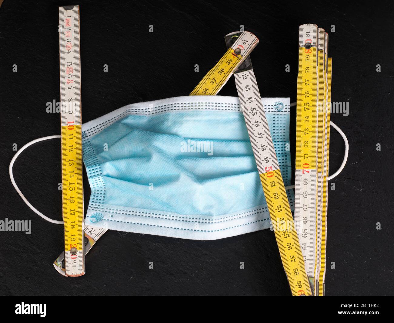 coronavirus icons as facial mask and folding meter on black background ...