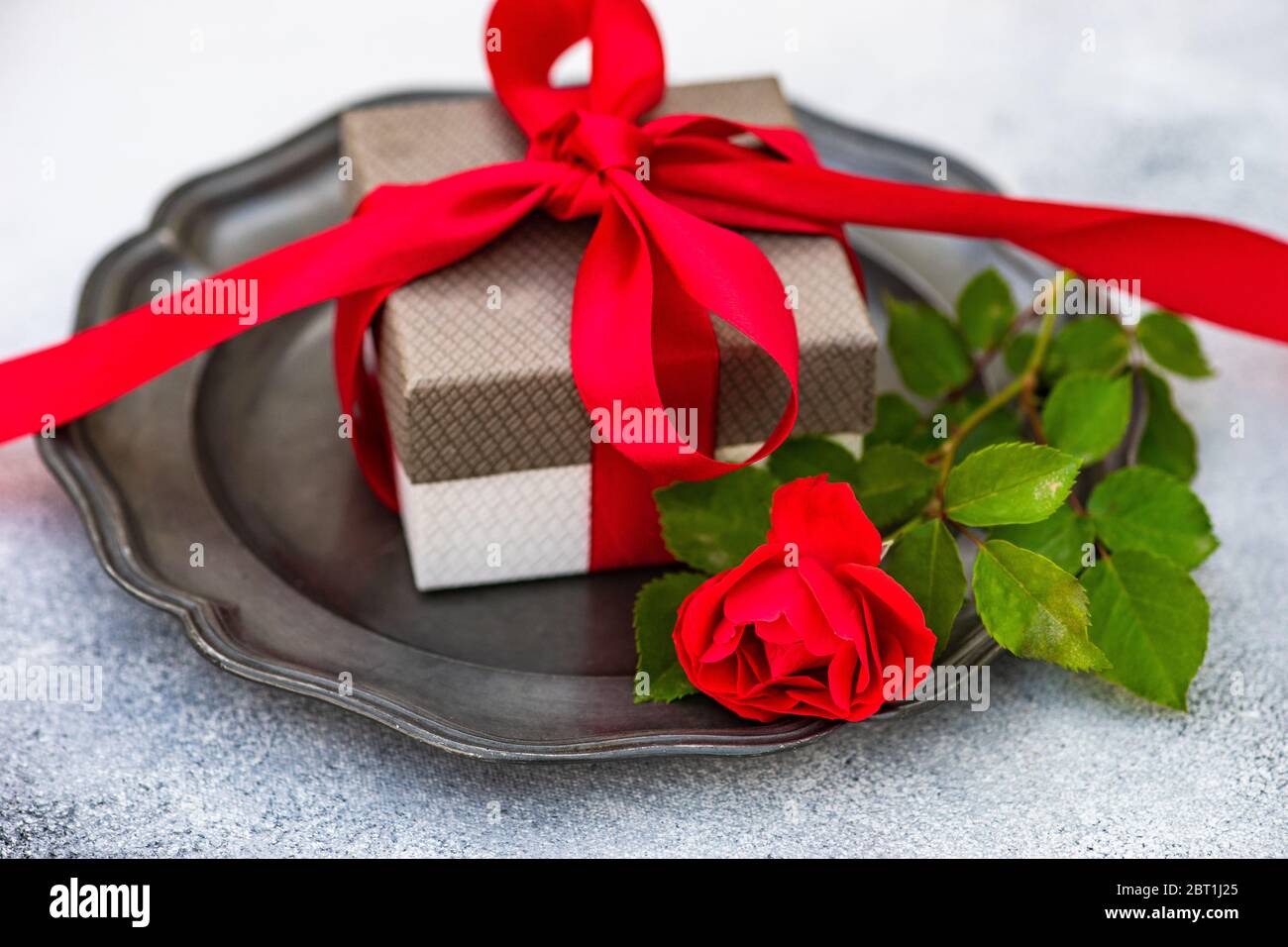 Table setting with fresh red rose flower on metal vintage plate on ...