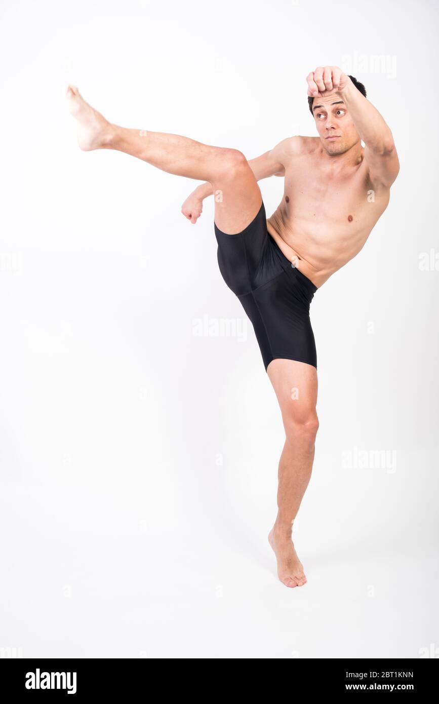Shirtless athlete man throwing a kick in the air. Full body, white ...