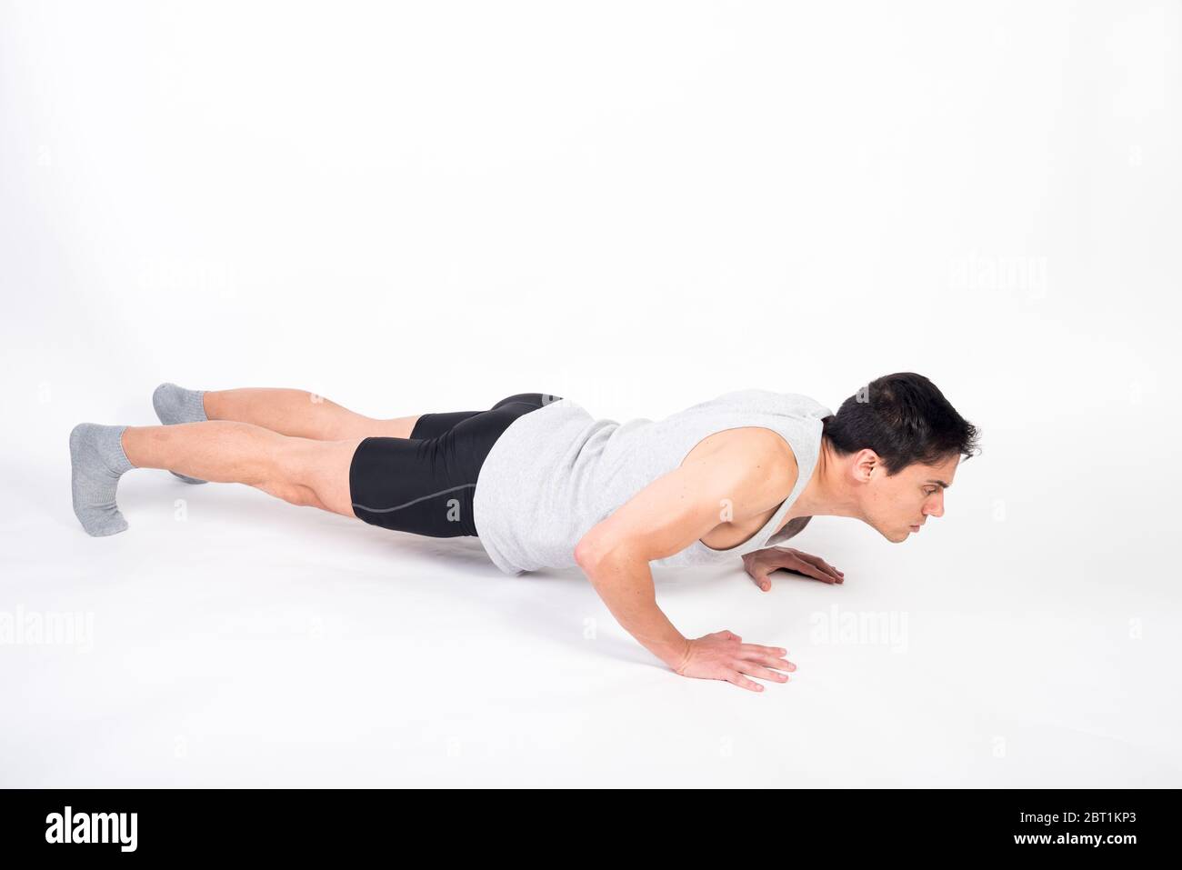 Athlete man doing push-ups on the floor. Full body, white background ...