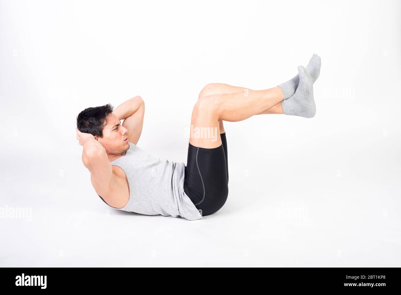 Man in sportswear doing sit-ups on the floor. White background, full ...