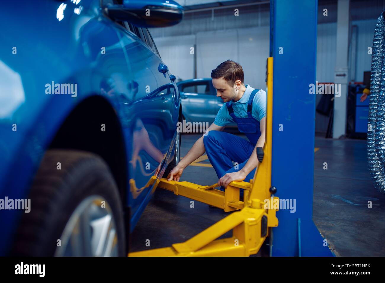 Worker in uniform fix vehicle on lift, car service station. Automobile ...