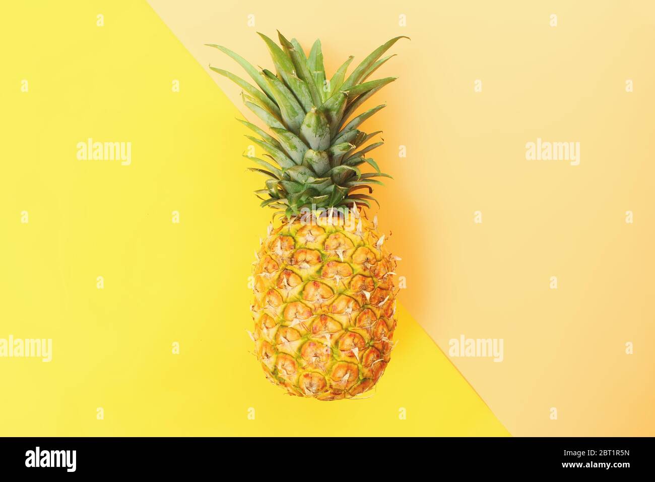 Pineapple in a two different tone of yellows background Stock Photo - Alamy