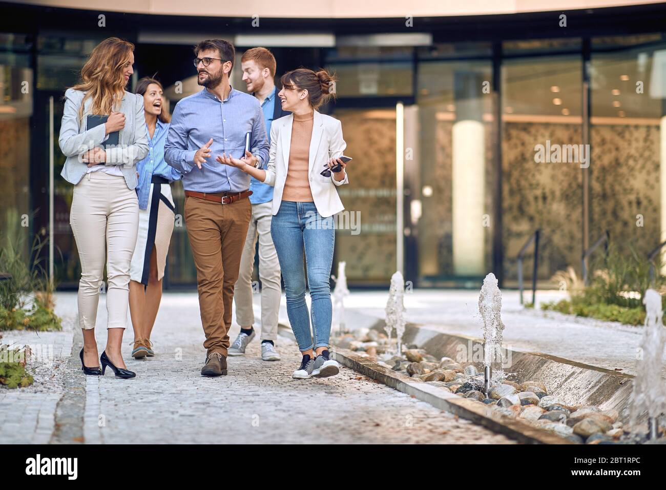 group of young businesspeople walking out of the building to have a ...