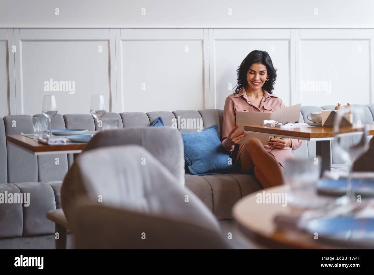 Cheerful young woman reading menu in restourant Stock Photo - Alamy