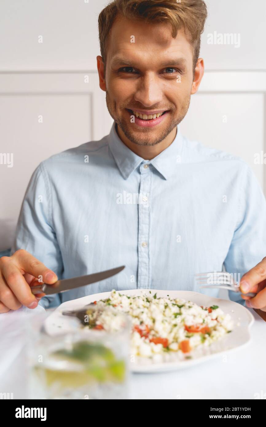 Joyful young man eating delicious food in cafe Stock Photo - Alamy