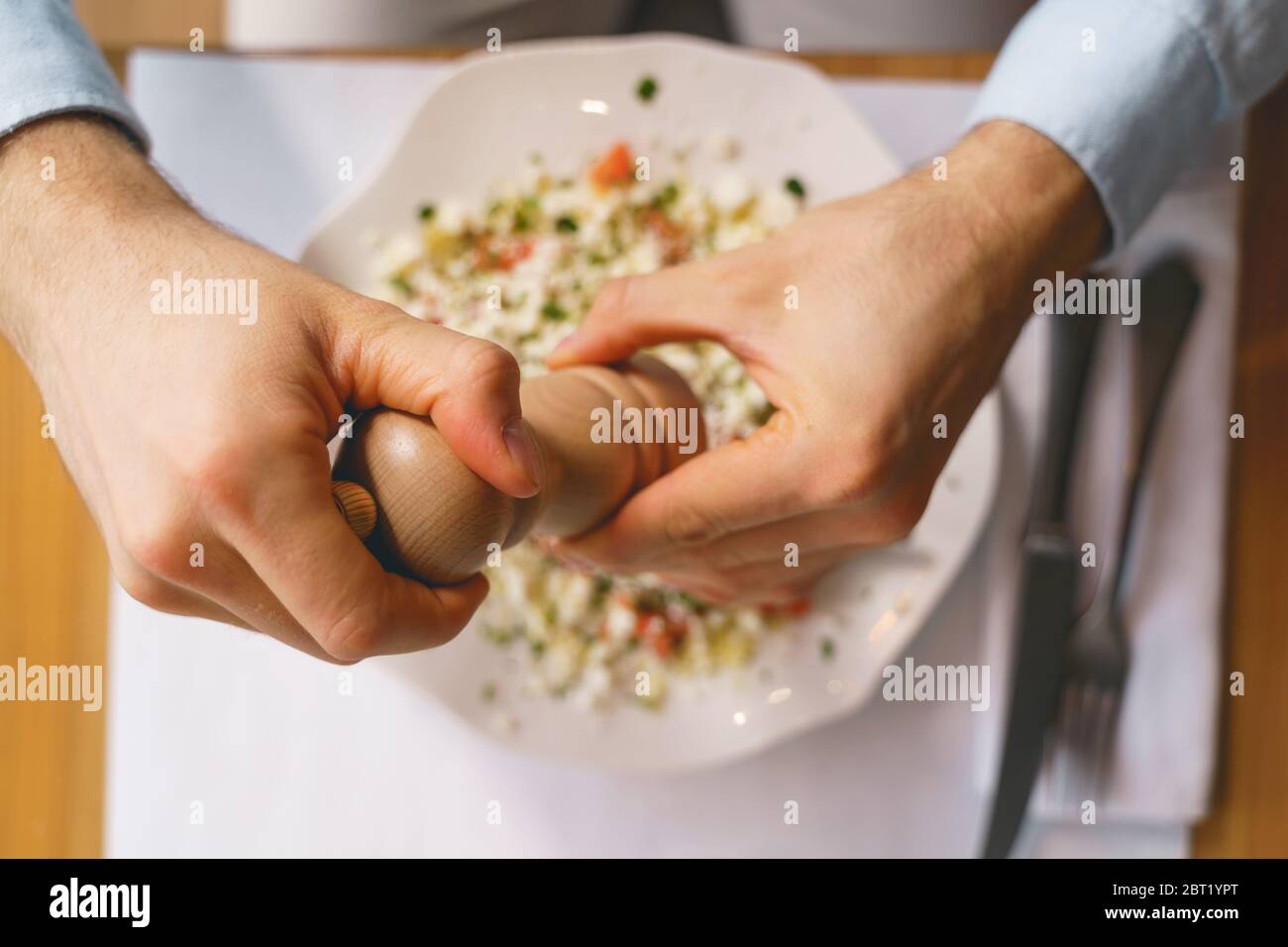 Young man using salt shaker while having lunch in cafe Stock Photo - Alamy