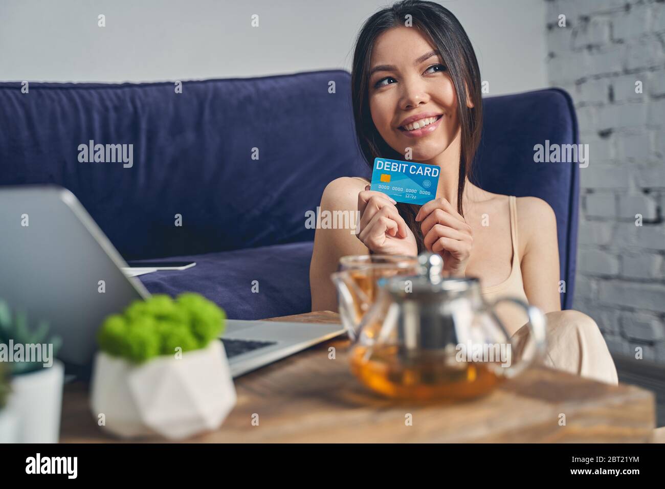 Attractive young woman holding debit card and smiling Stock Photo - Alamy