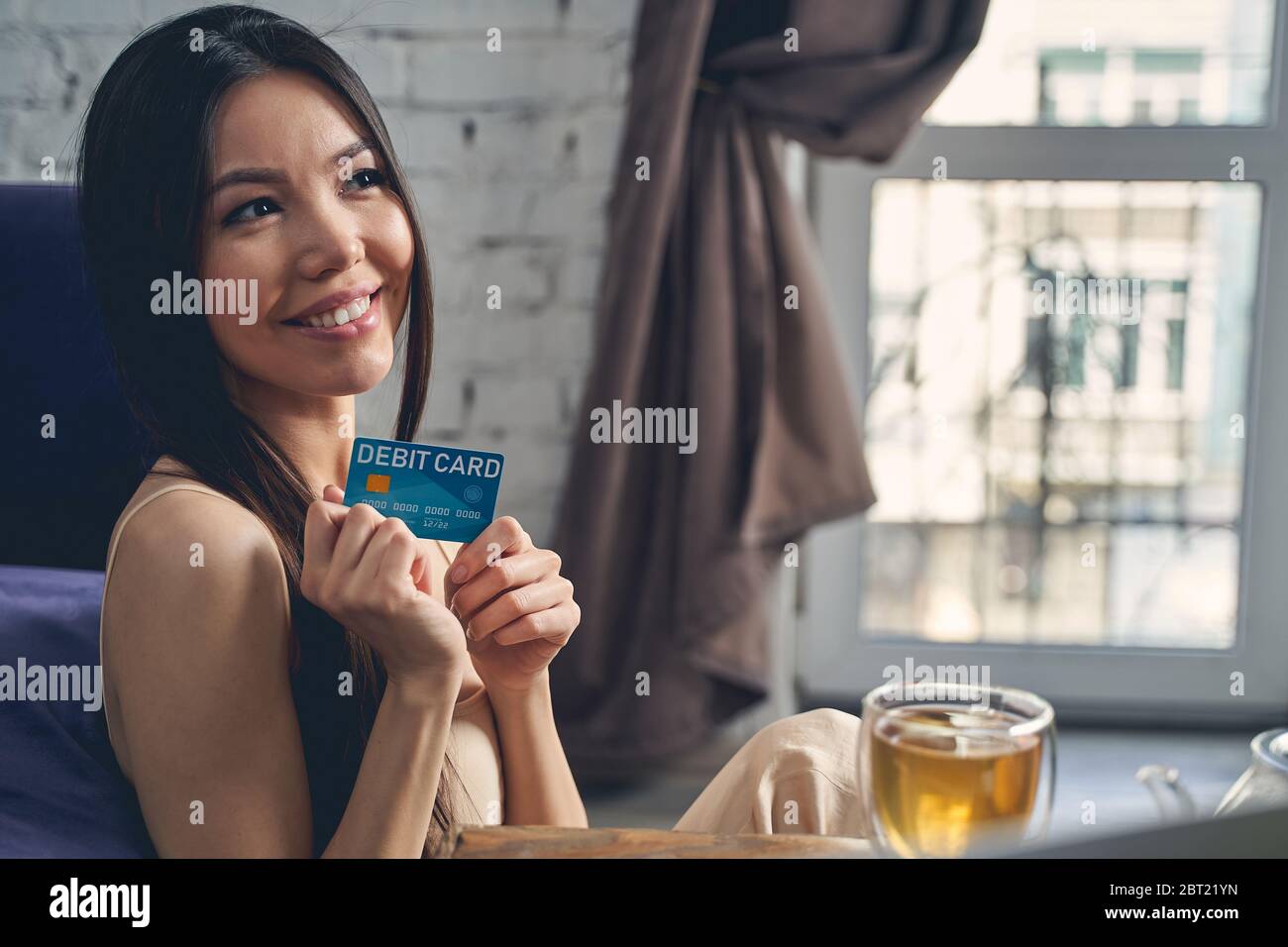 Beautiful young woman holding debit card and smiling Stock Photo - Alamy
