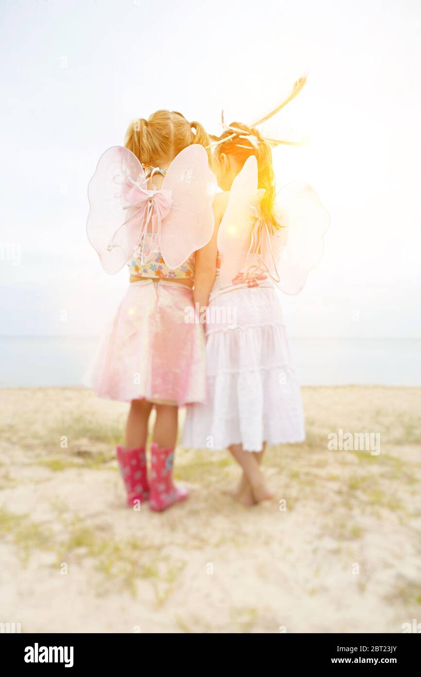 Rear view of two little girls dressed as angels with lens flare Stock ...
