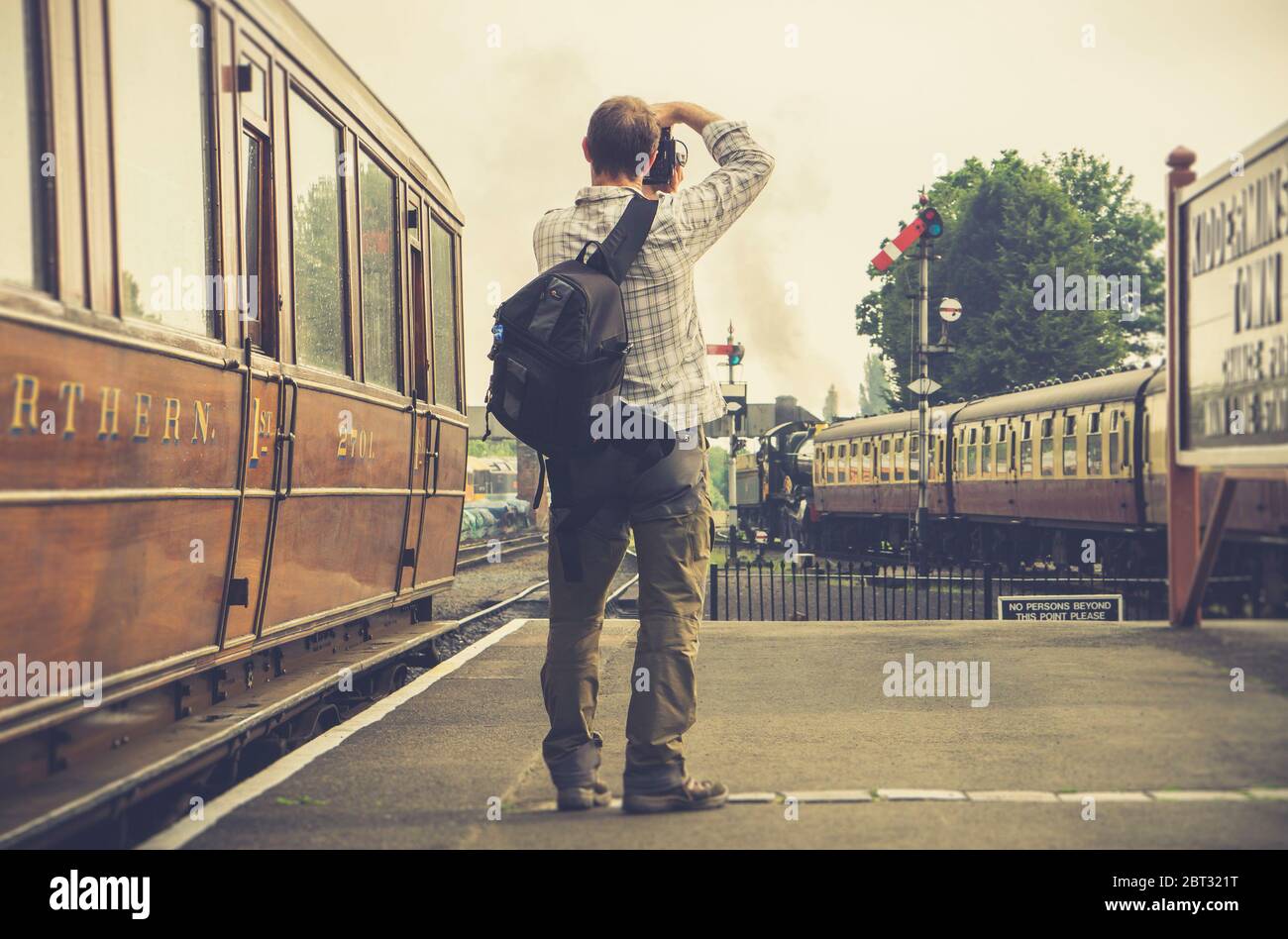 Rear view of isolated man standing on platform at heritage railway ...