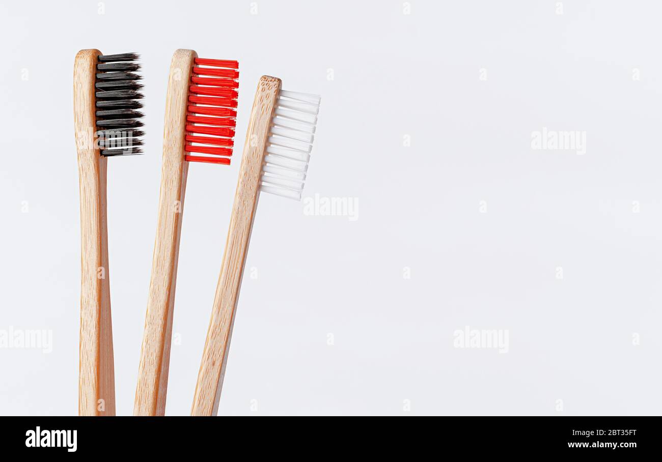 Red, white and black bamboo toothbrushes on white background. Copy ...