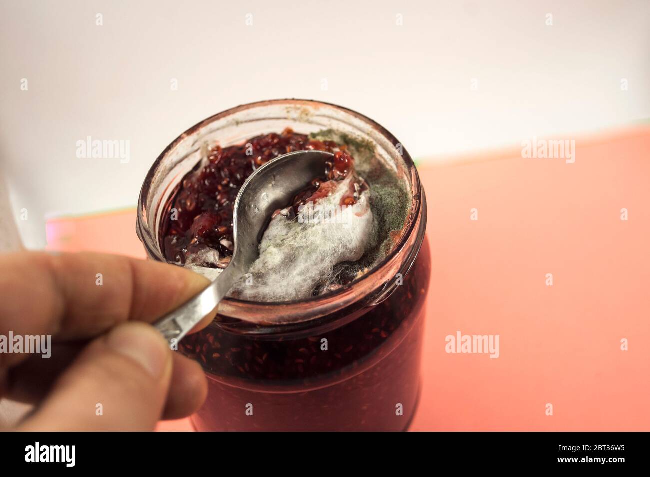 A jar without a lid with raspberry jam, which is covered with threads ...