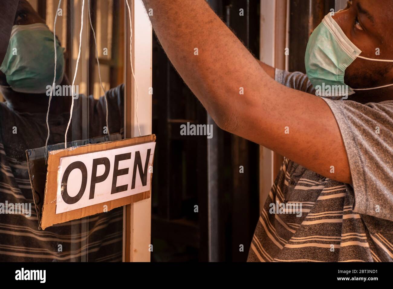 a local african business owner putting up a open sign in front of his ...