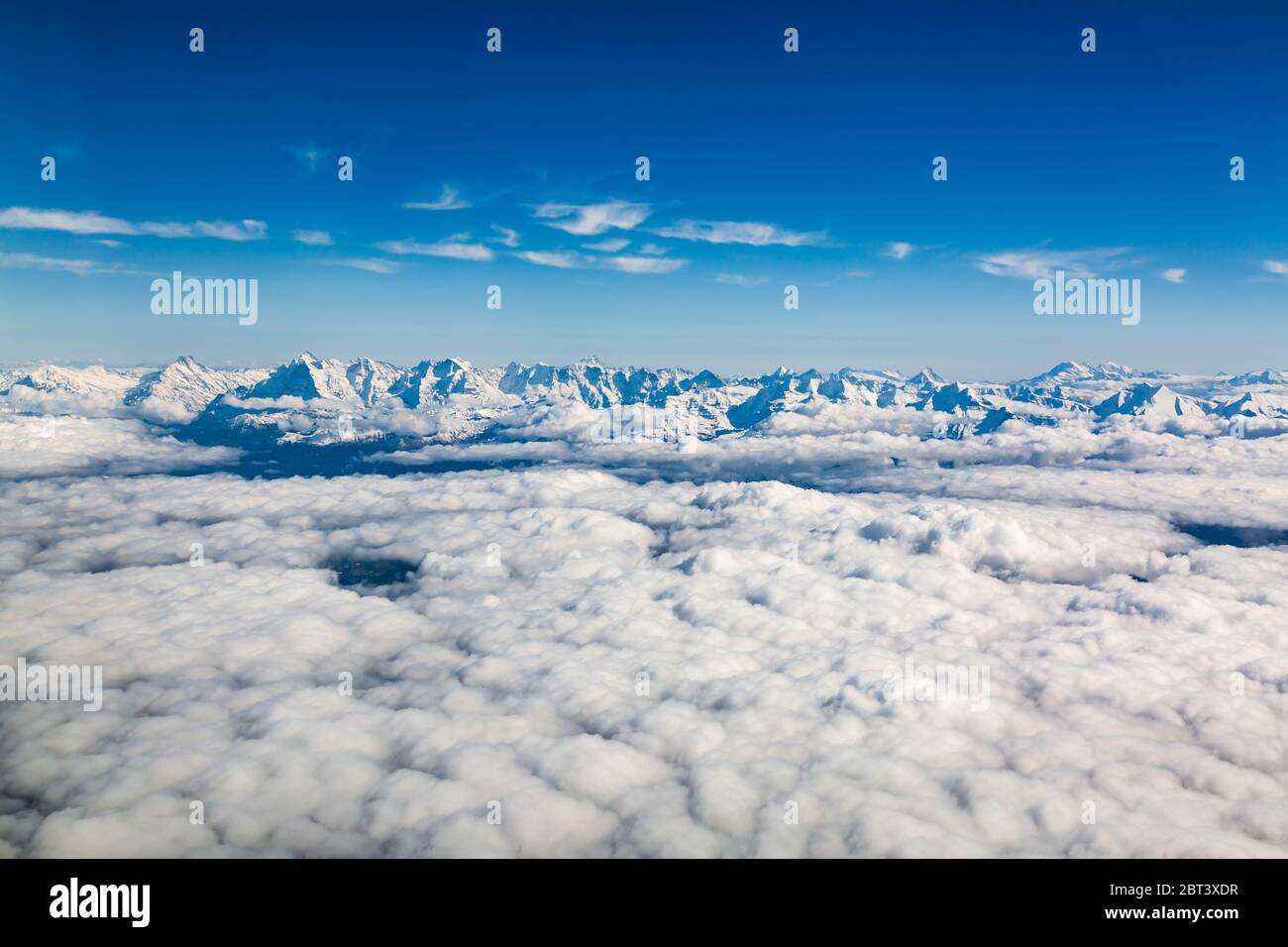 Aerial view of Alps mountain range above clouds seen from airplane over ...