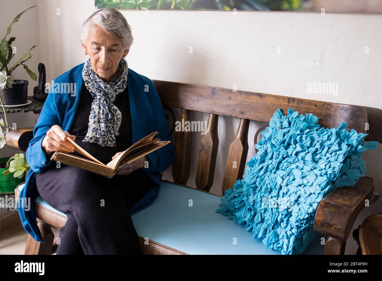 Senior woman alone at home reading an old book Stock Photo - Alamy