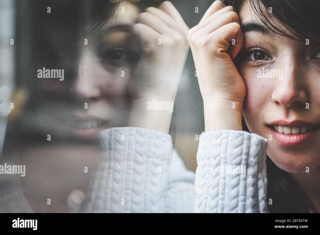 Portrait of a woman looking out of a window Stock Photo - Alamy