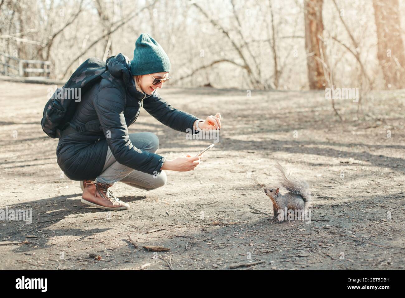 Caucasian woman taking picture photo of squirrel in park. Tourist ...