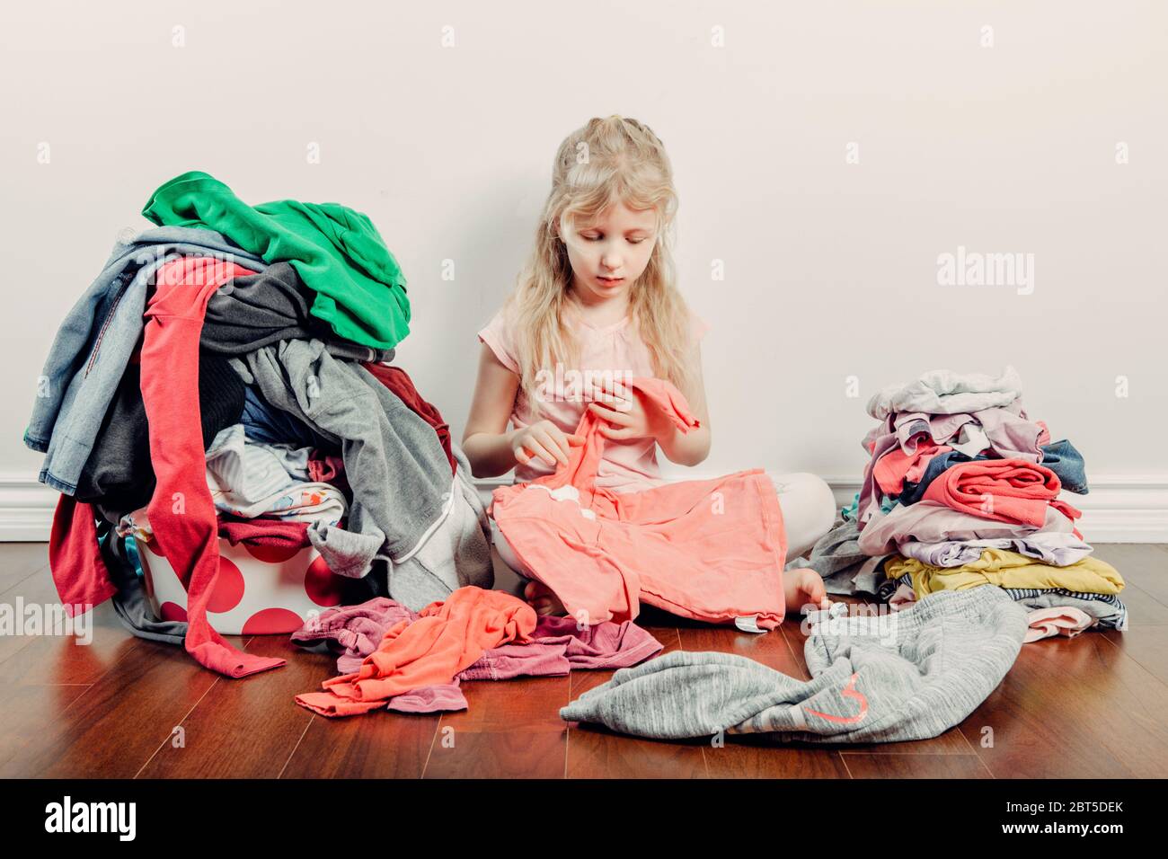 Mommy little helper. Cute Caucasian girl sorting clothes. Adorable ...
