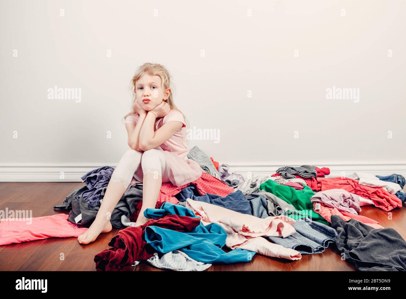 Mommy little helper. Bored Caucasian girl sorting clothes. Tired funny ...