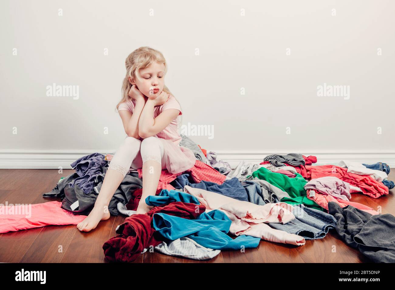 Mommy little helper. Bored Caucasian girl sorting clothes. Tired funny ...