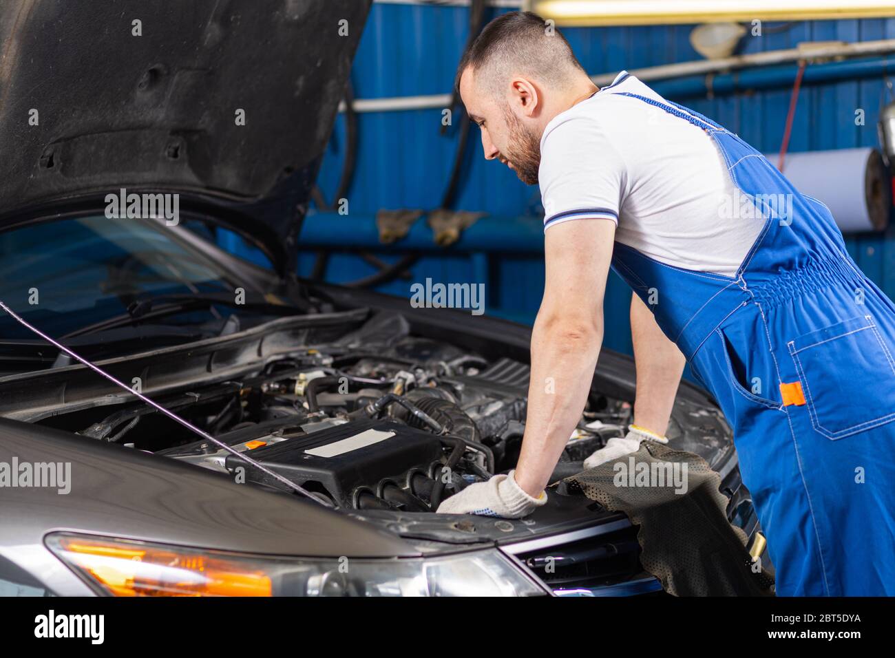 Handsome young male auto mechanic in special uniform clothes looking ...