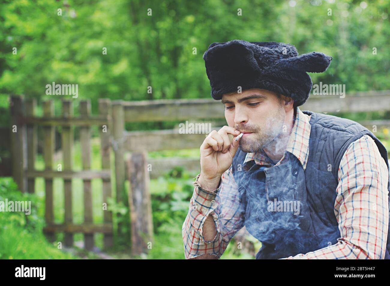 lumberjack in a hat smokes in the woods Stock Photo - Alamy