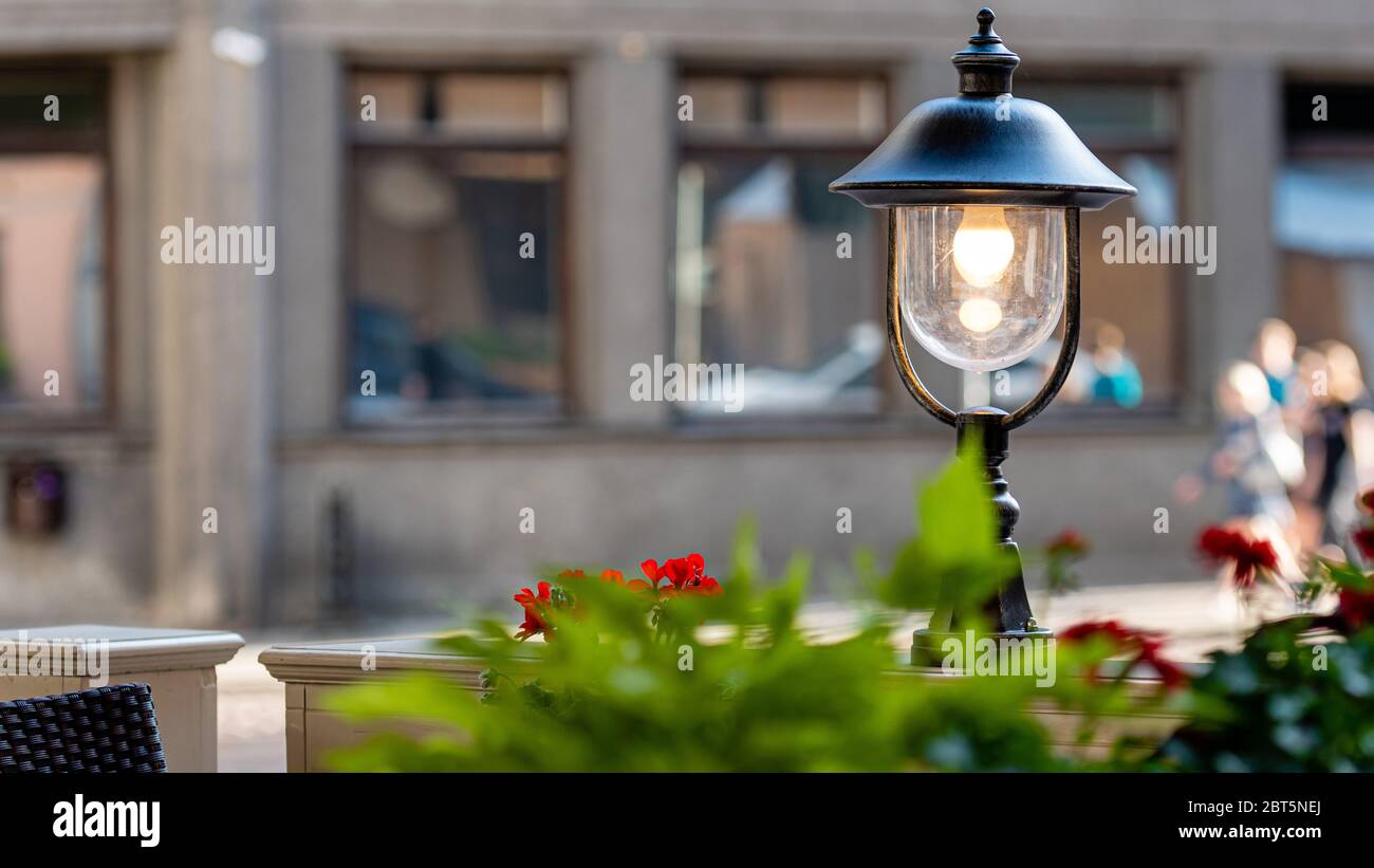 street cafe decorated with lanterns and plants, defocused street ...