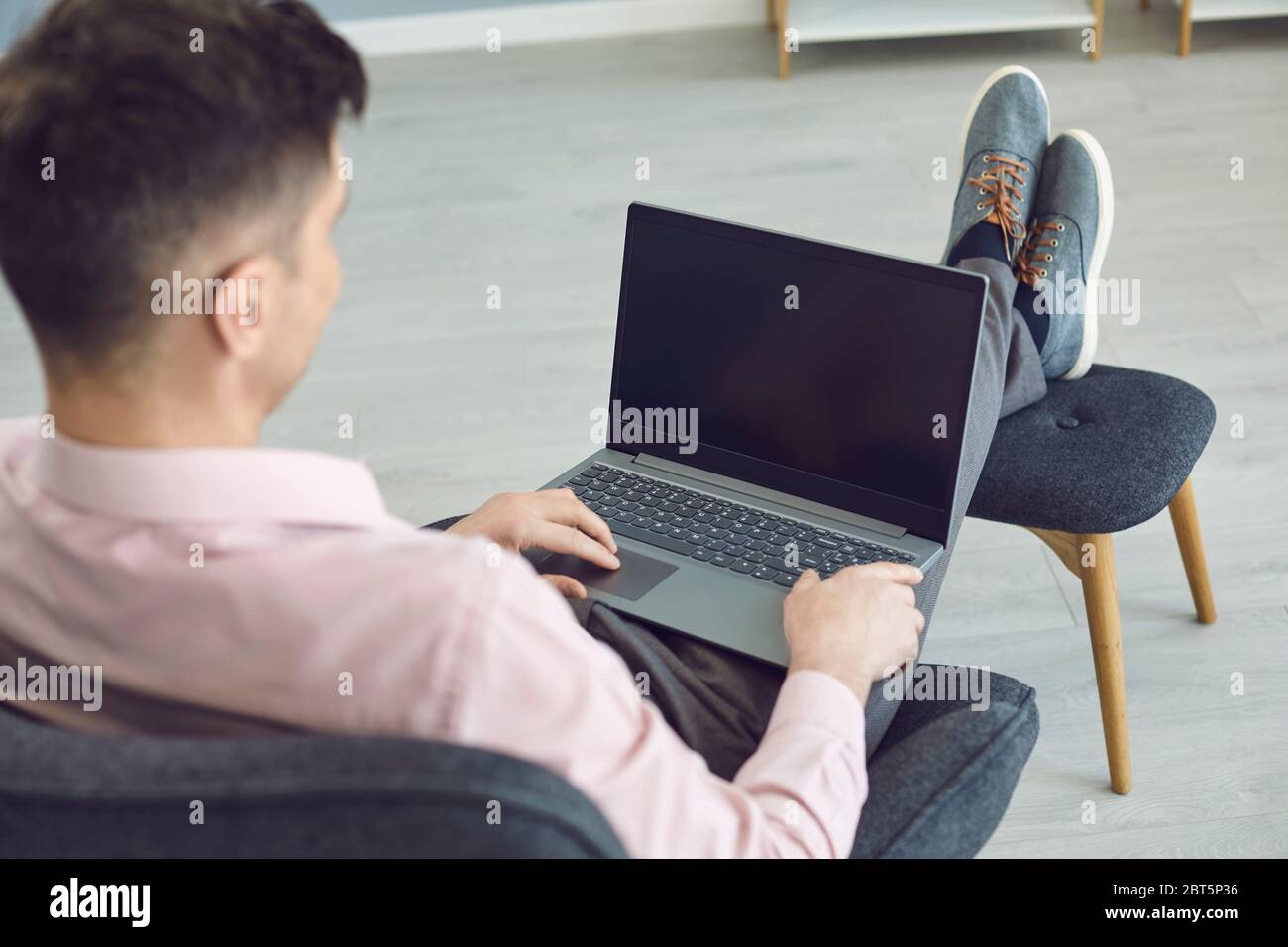 High angle of unrecognizable relaxed male sitting in armchair with legs ...