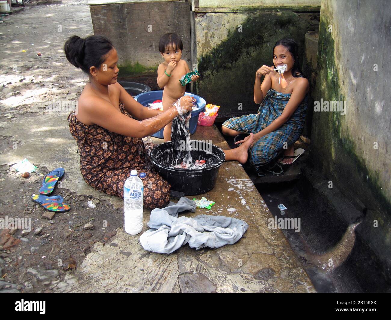 young woman teenager cleaning her teeth with mother doing laundry and ...