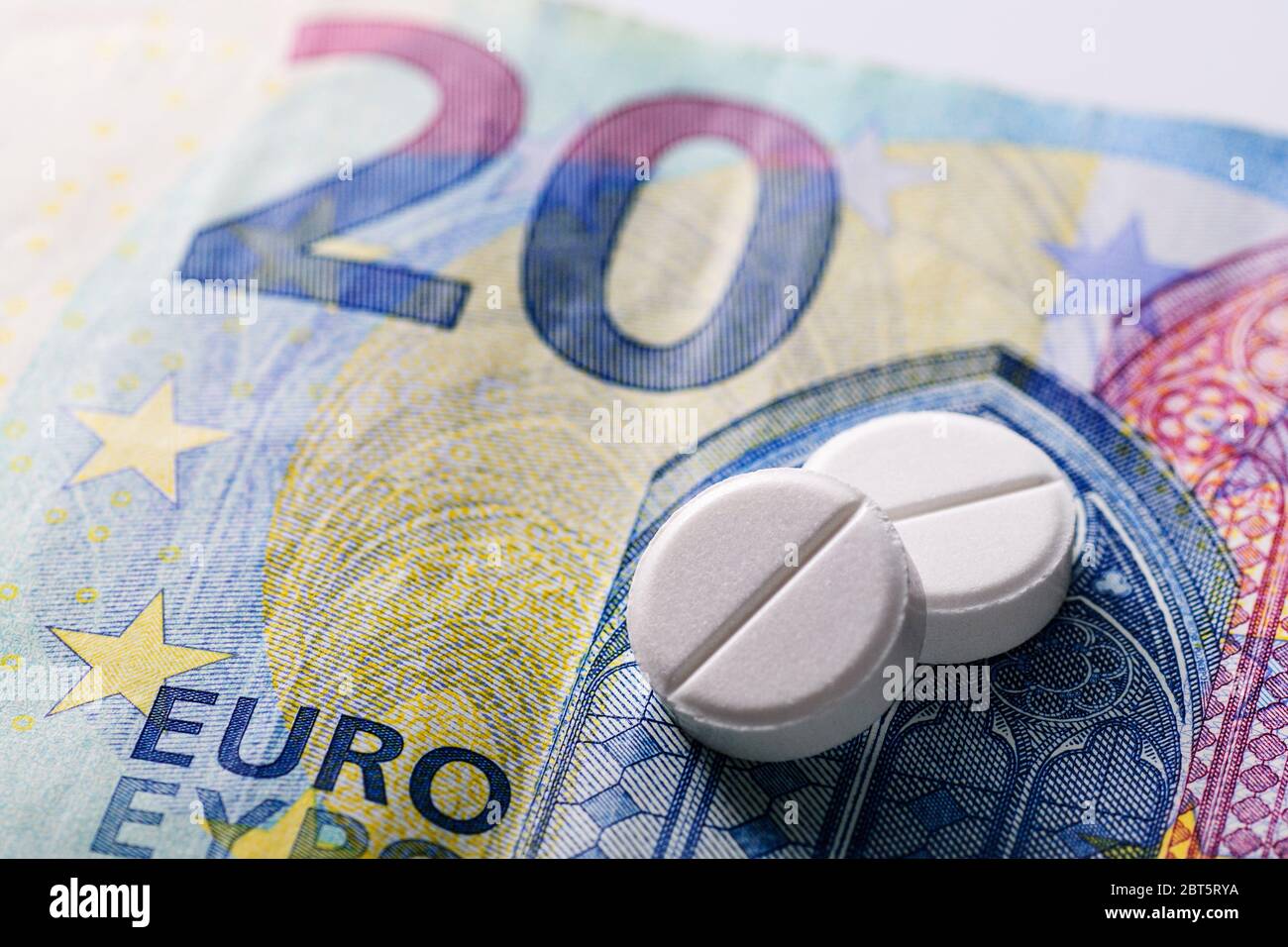 Two generic white tablets on a 20 Euro note in a concept of payment of ...