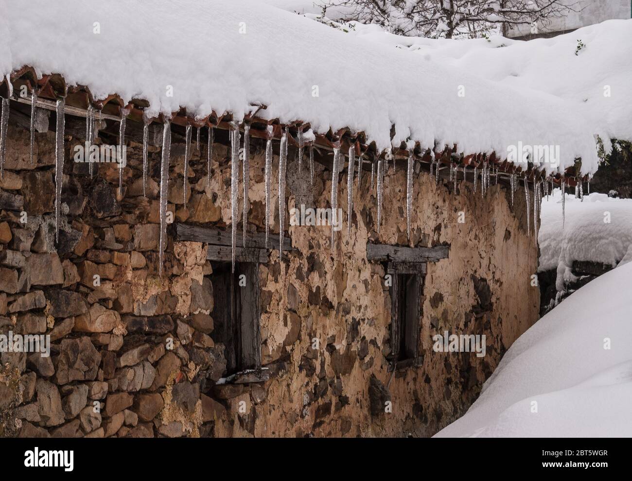 Ice icicles on the eaves of a snowy roof Stock Photo - Alamy