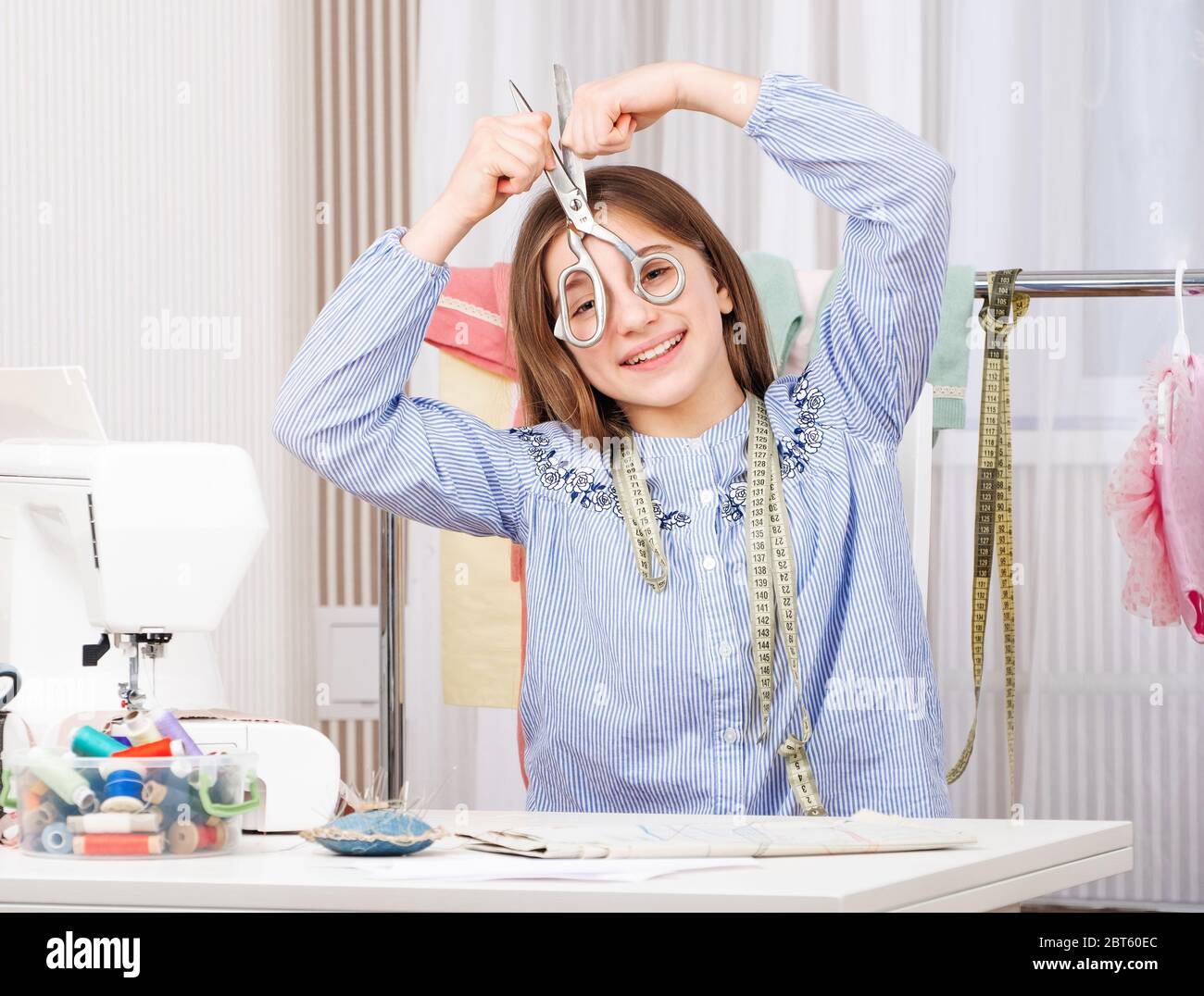 Cute young tailor with scissors at workspace Stock Photo - Alamy