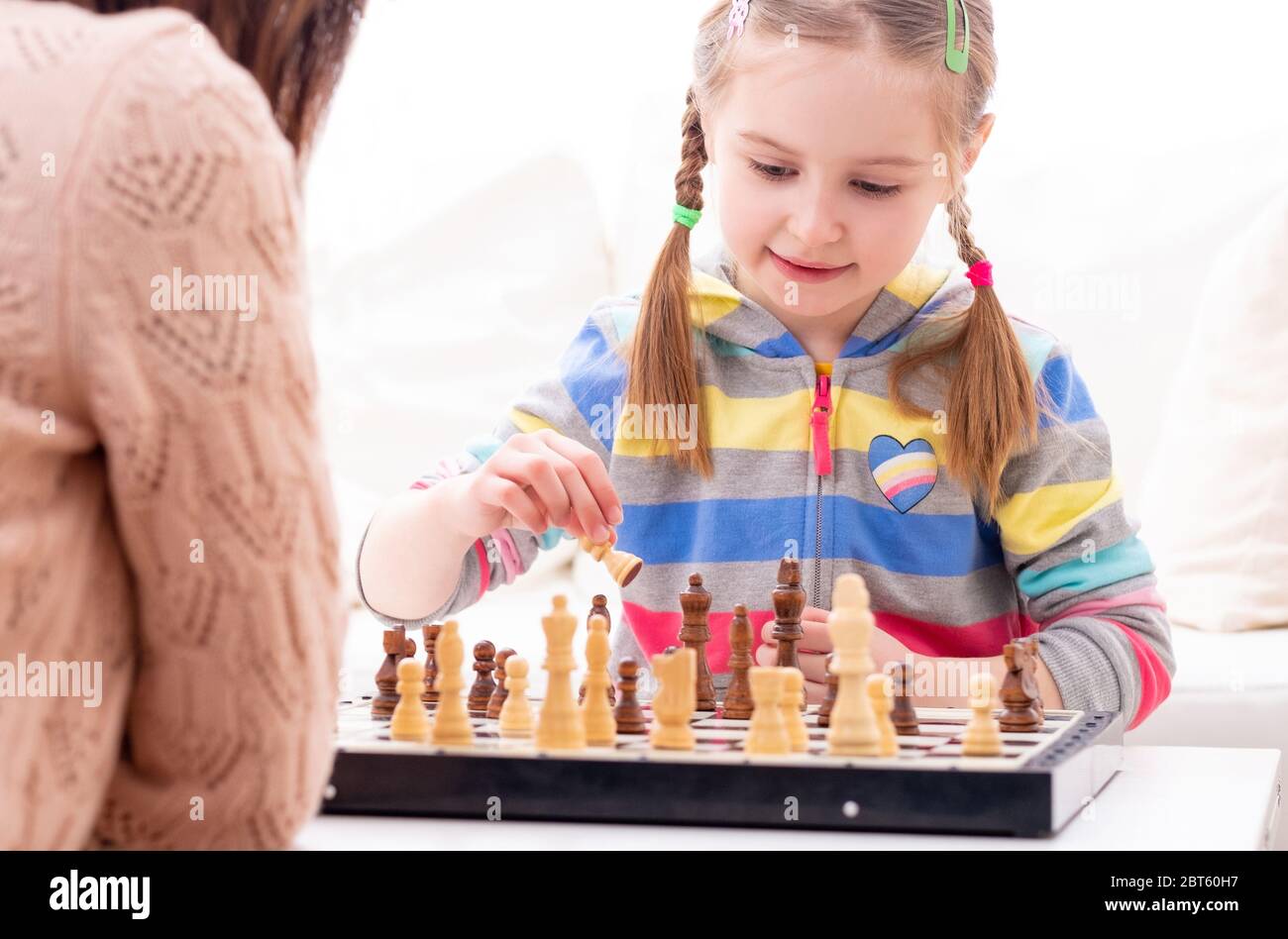 Lovely mother is playing smart chess game with her adorable daughter ...