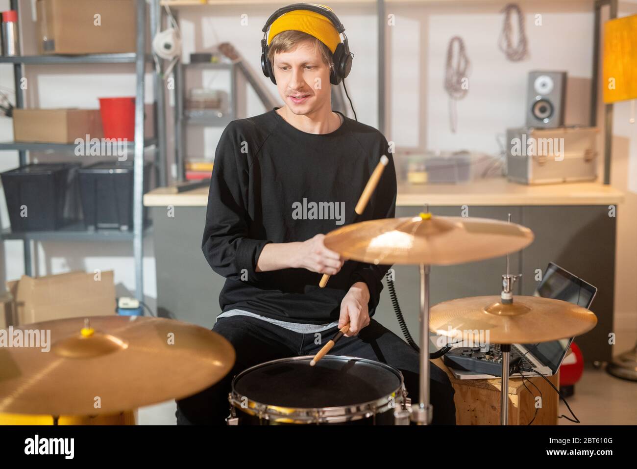Young man in headphones, yellow beanie, black sweatshirt and jeans ...