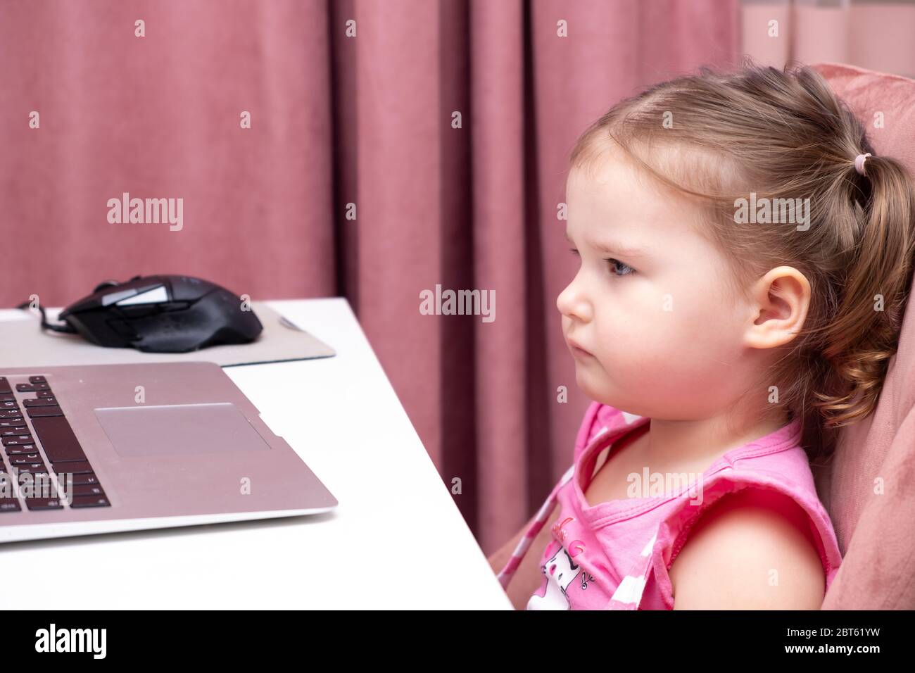 Beautiful cute sad little girl at a laptop. The concept of the ...