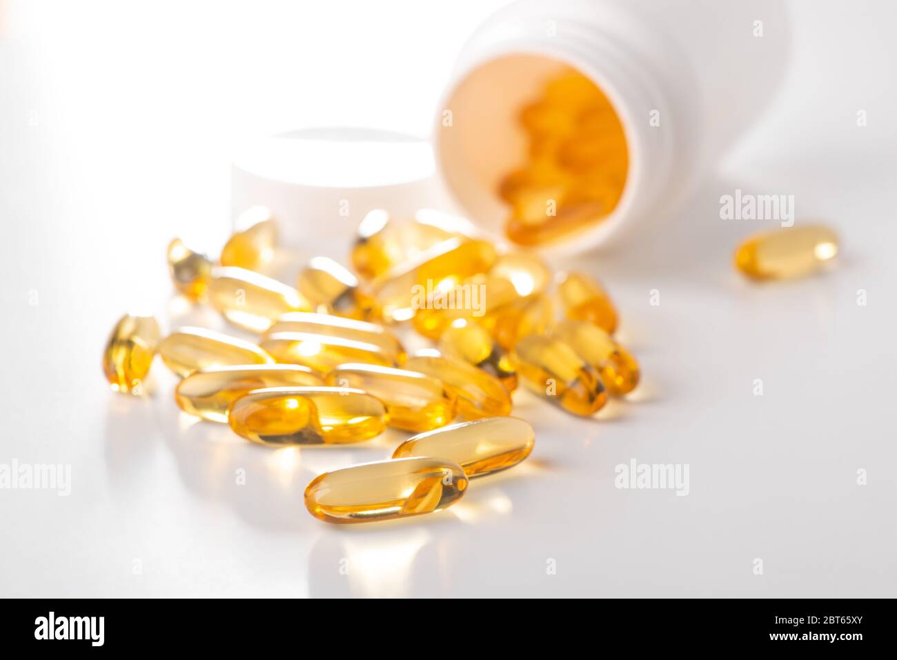 Yellow capsules scattered from a bottle on white background Stock Photo ...