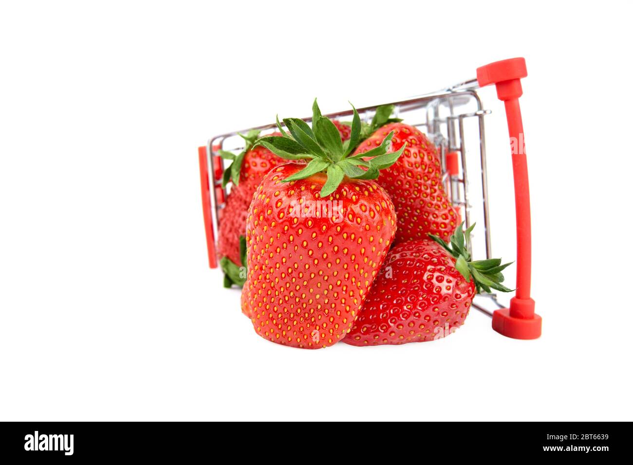 Toy shopping cart full of fresh strawberries isolated on white. Close ...