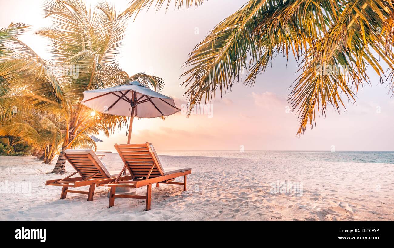 Beautiful tropical sunset scenery, two sun beds, loungers, umbrella ...