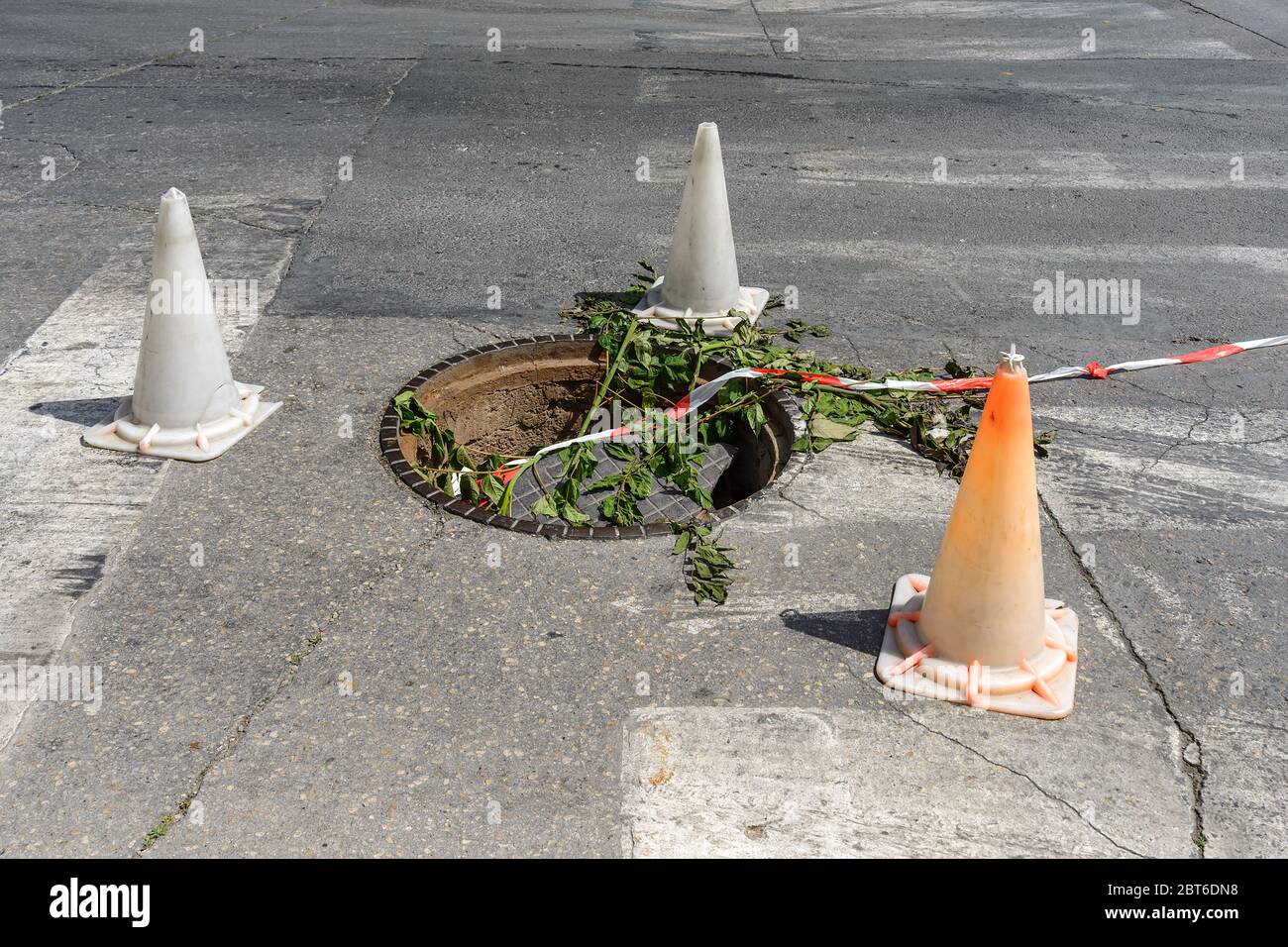 Open manhole marked with old traffic cones on a city street. Manhole ...