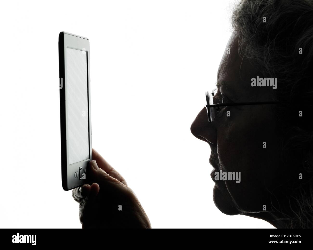 Woman in silhouette wearing glasses reading from hand held small ...