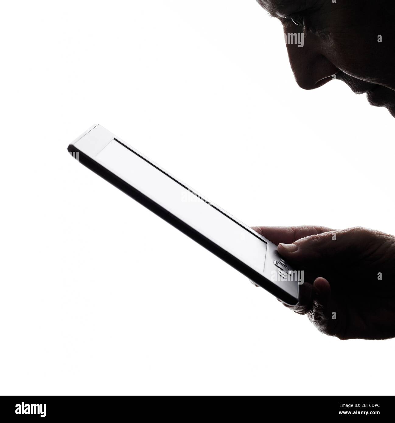 Woman in silhouette reading from hand held small digital tablet screen ...