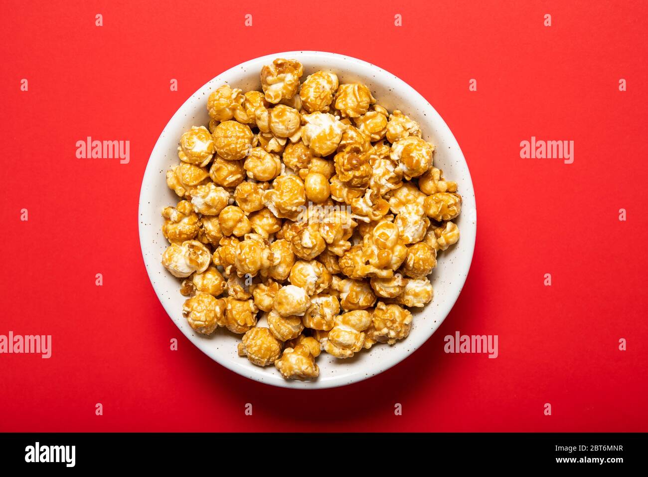 Plate with caramel popcorn on a red background Stock Photo - Alamy