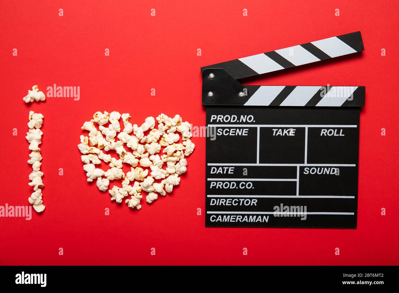 Plate with popcorn and movie clapper board on a red background Stock ...